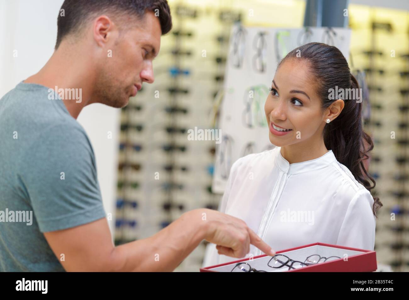 professional young female optician helping client to choose a ...