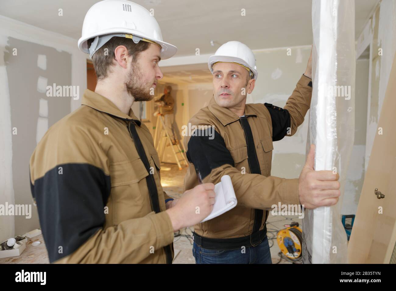 construction worker and apprentice talking notes Stock Photo - Alamy