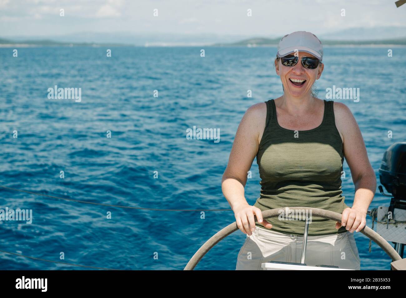 Female skipper on the steering wheel of a yacht. Sailing and yachting ...