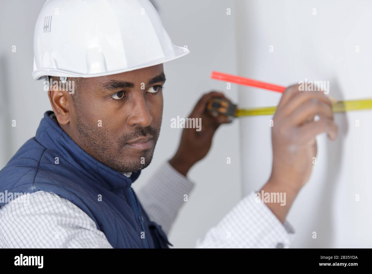 a man builder is measuring a wall Stock Photo - Alamy