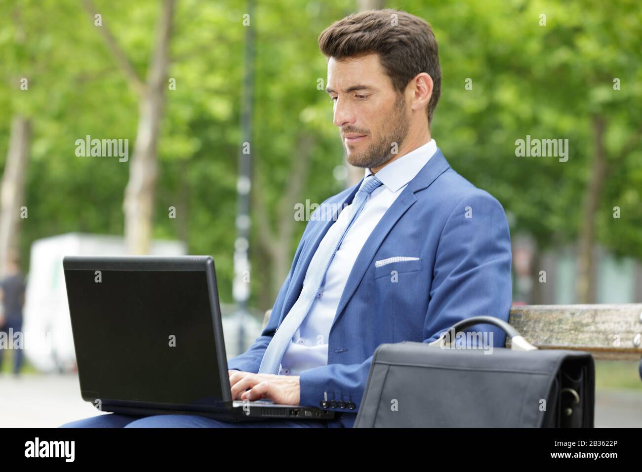 stylish man with laptop on bench Stock Photo - Alamy