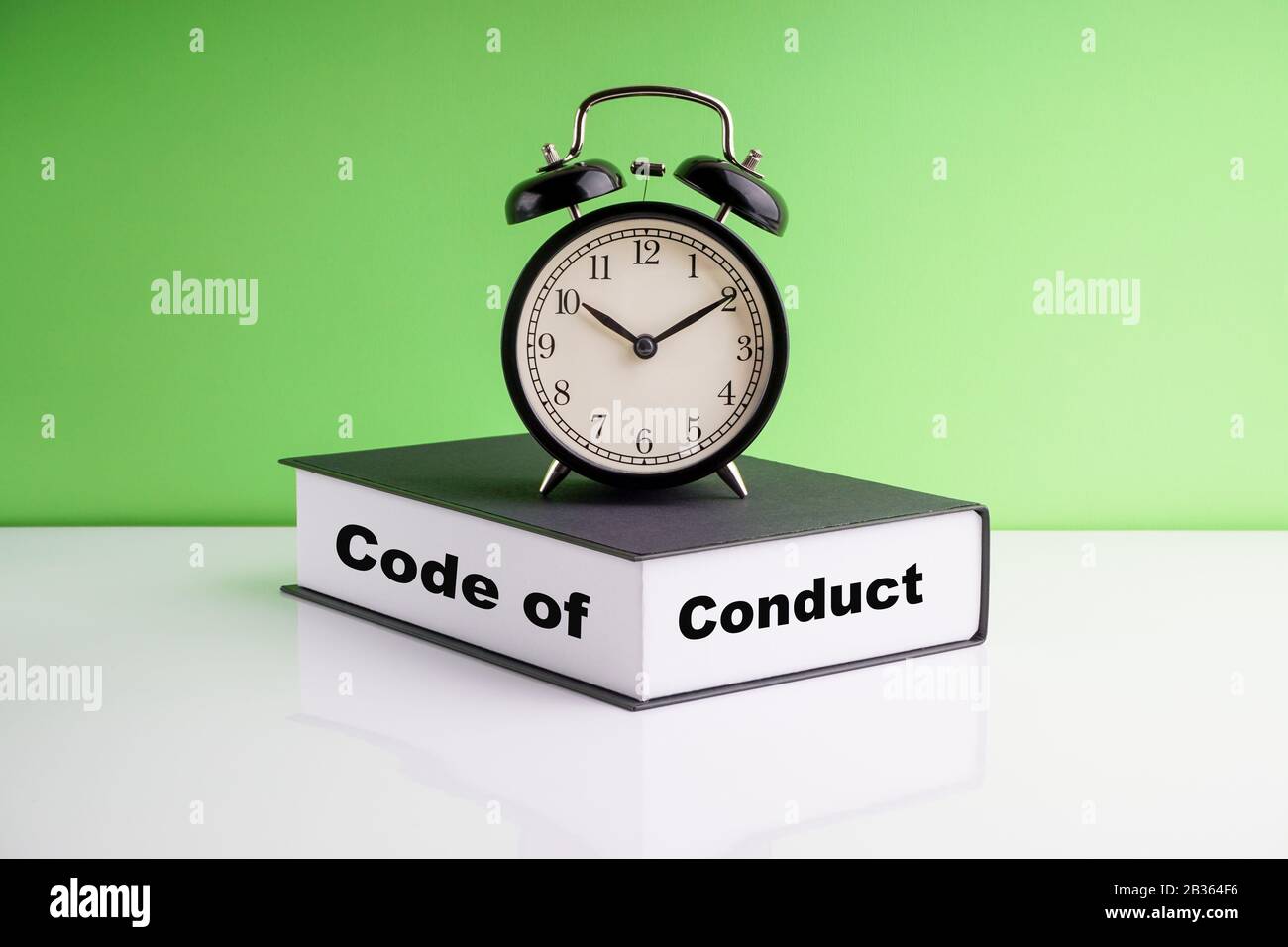 CODE OF CONDUCT text, Alarm Clock and book on green background. Copy ...