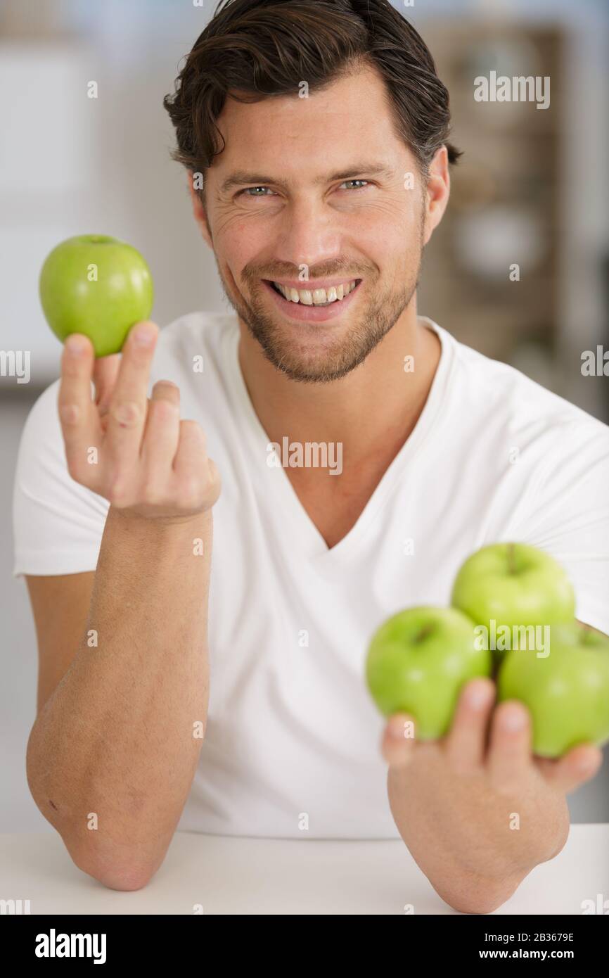 young smiling man holding green apples Stock Photo - Alamy