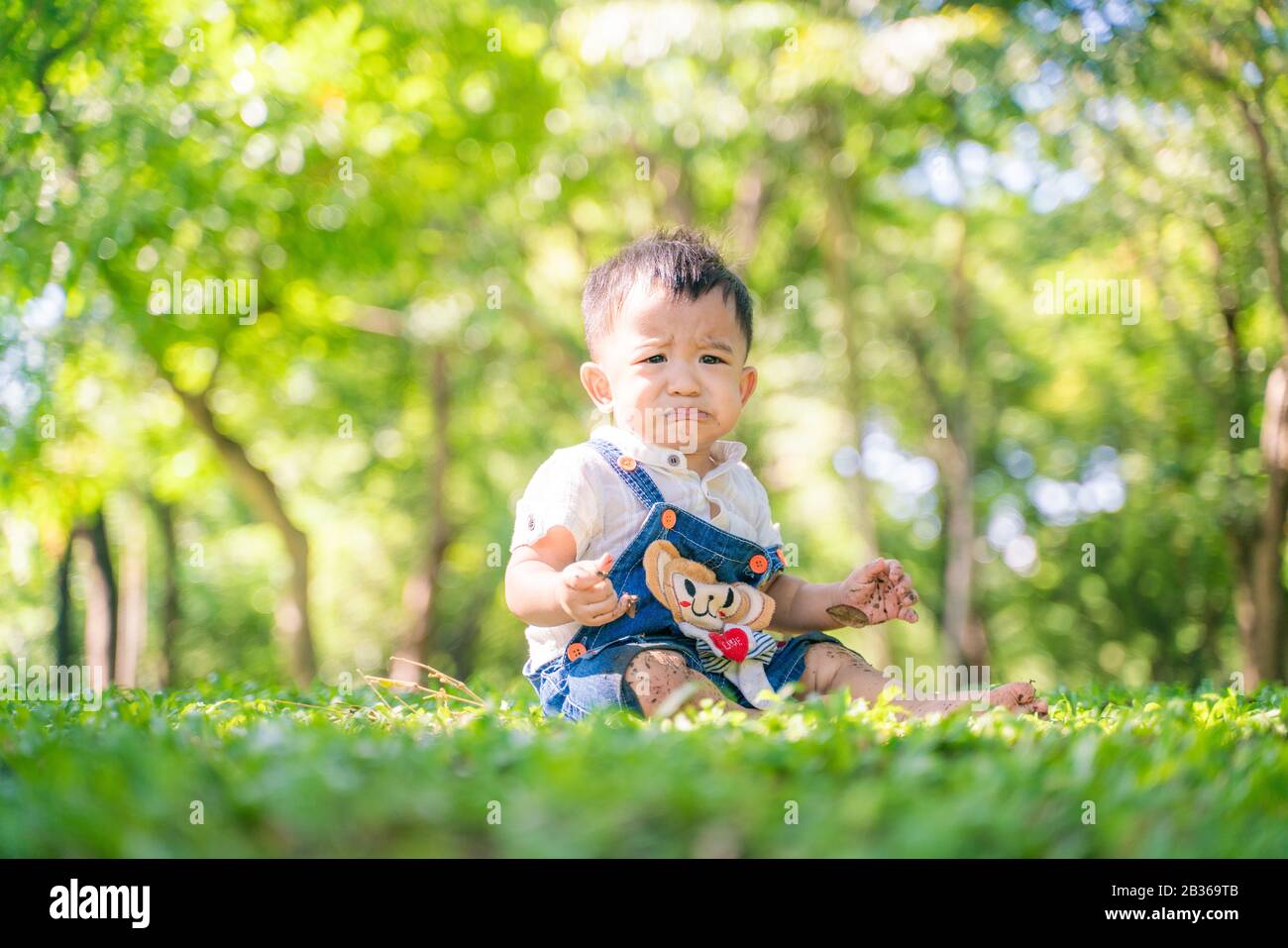 Kid child boy enjoying with nature green grass under tree in city park ...