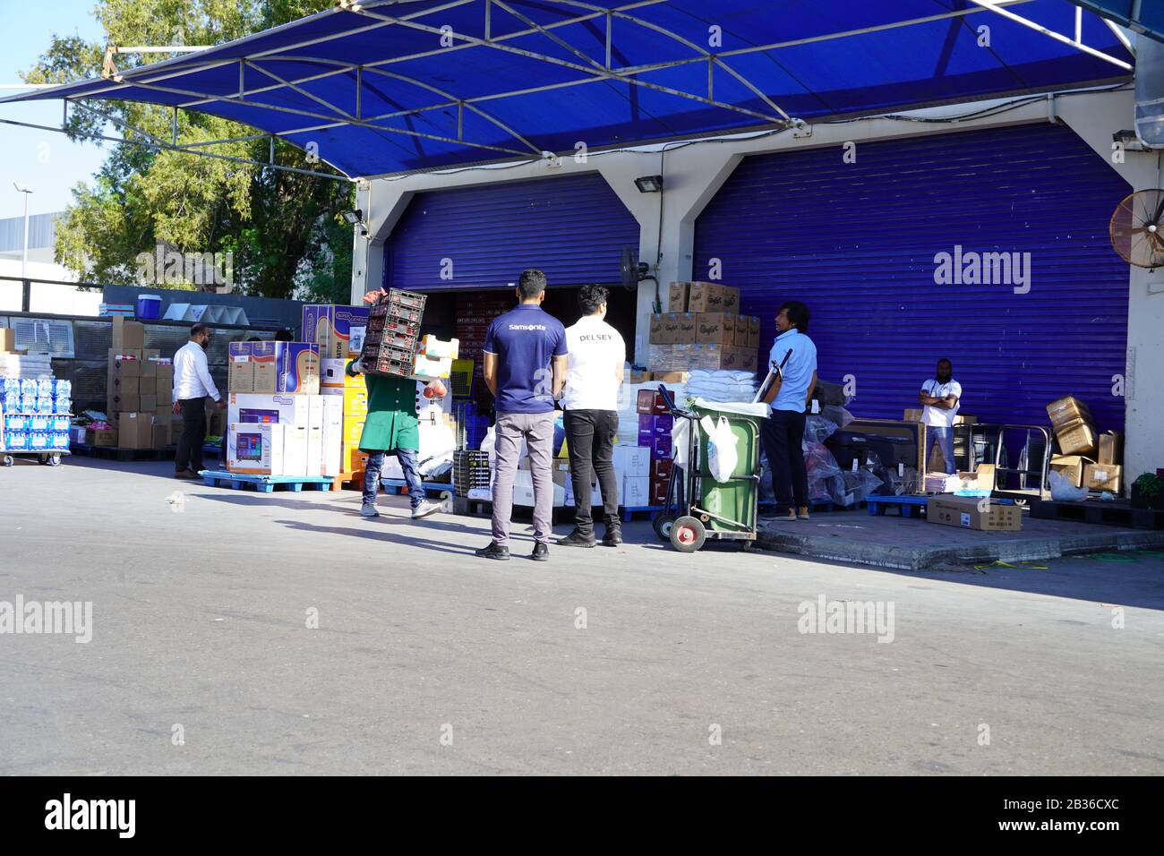 Workers with manual forklift and boxes stockpile goods near storage ...