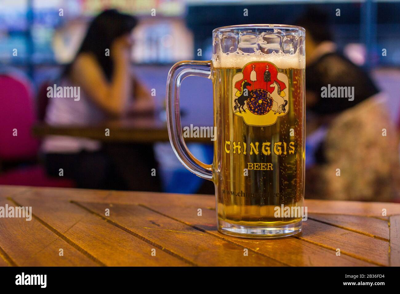 Mongolia, Ulan Bator, close-up of a glass of Mongolian Chinggis beer and two young women in the ...