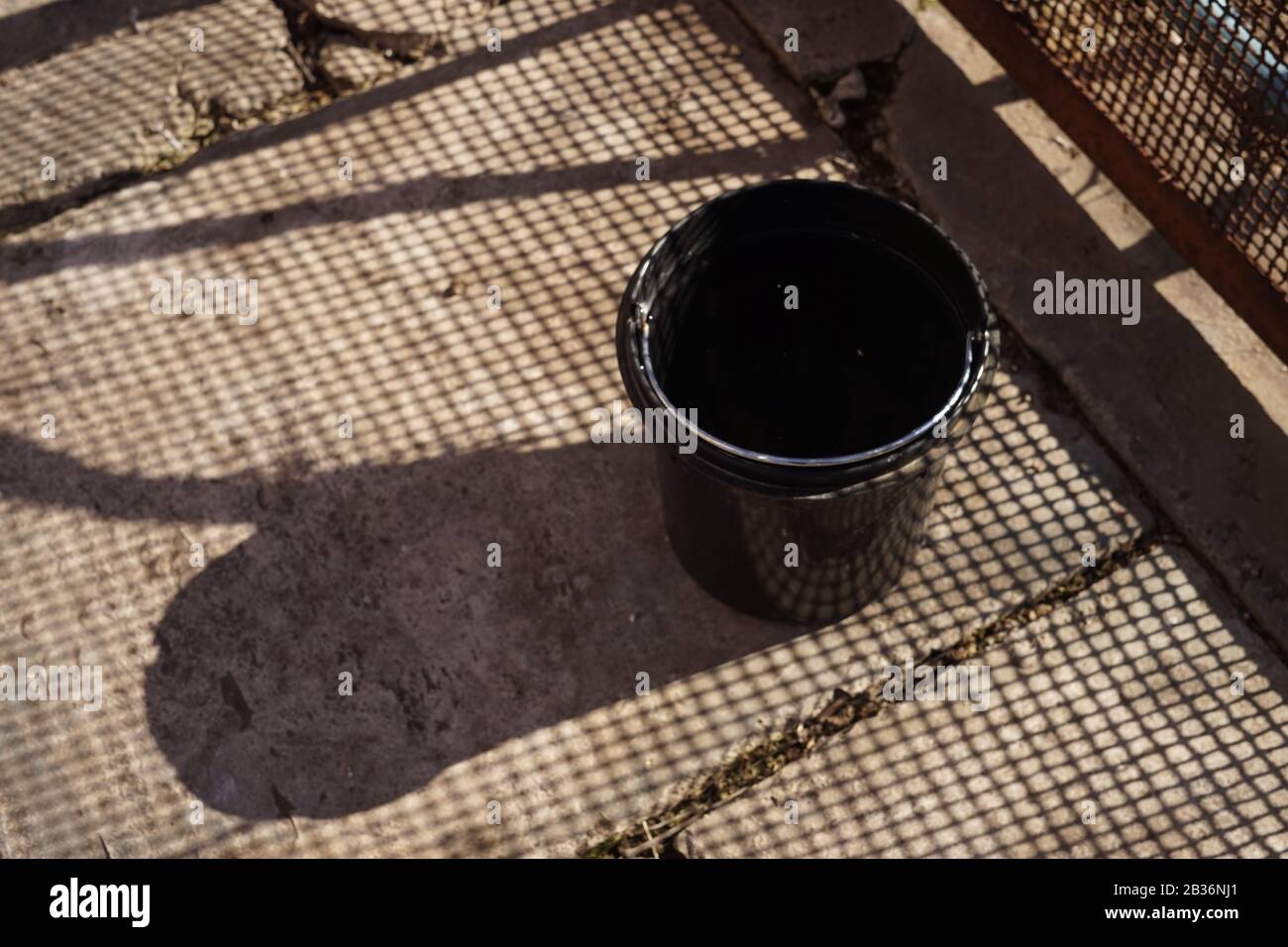 Plastic bucket on an old stone floor. Shadows from the mesh fence Stock ...