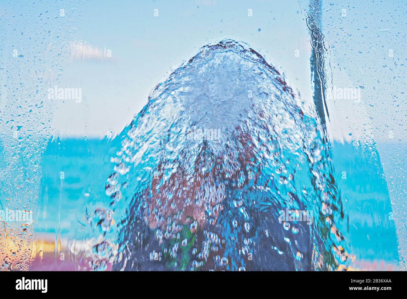 View of guy through window glass clean window with water by hose pipe ...