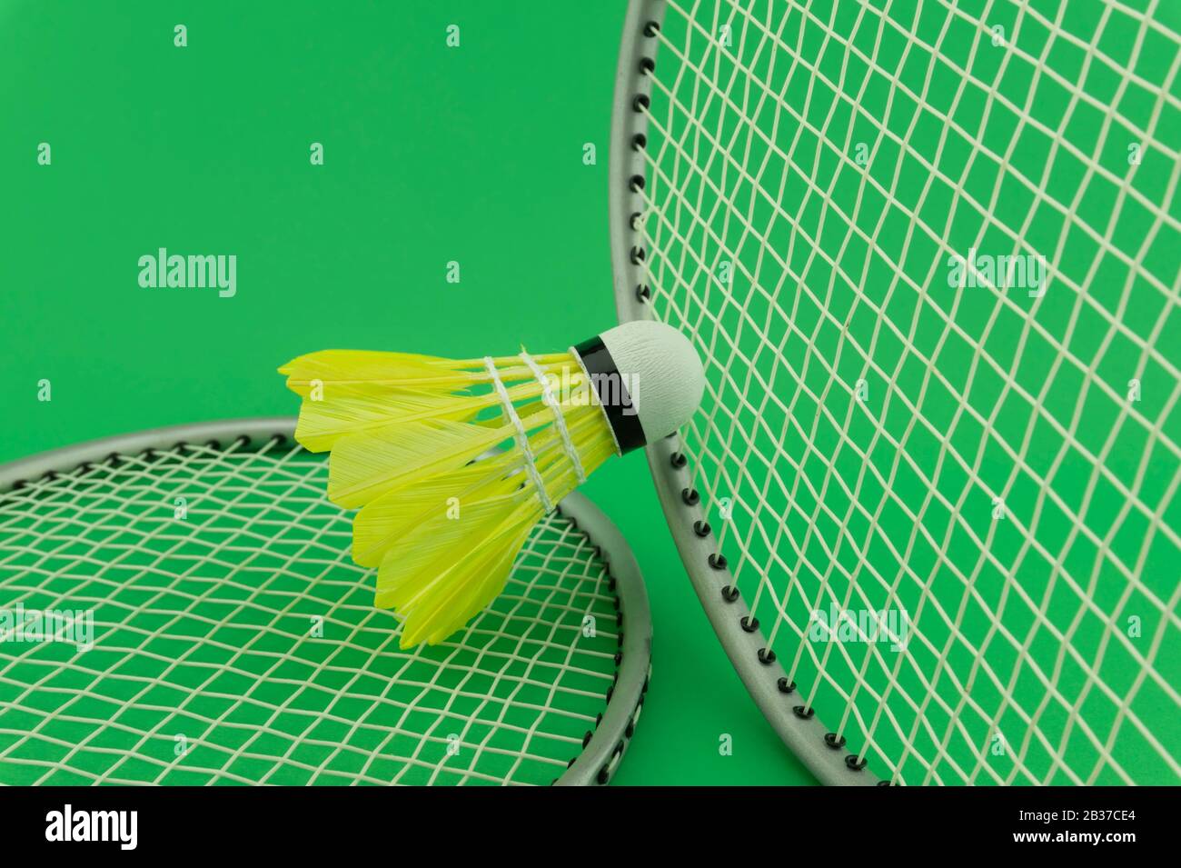 Badminton rackets and yellow feathered shuttlecocks on green background ...