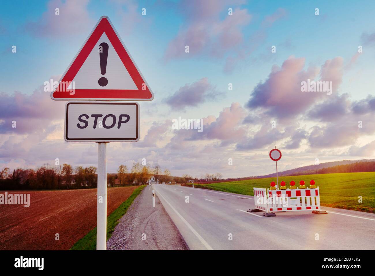 road block with street sign and warning lights on road at countryside ...
