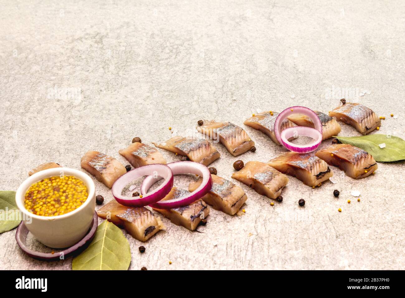 Pieces of pickled Norwegian salted herring with spices and onions ...