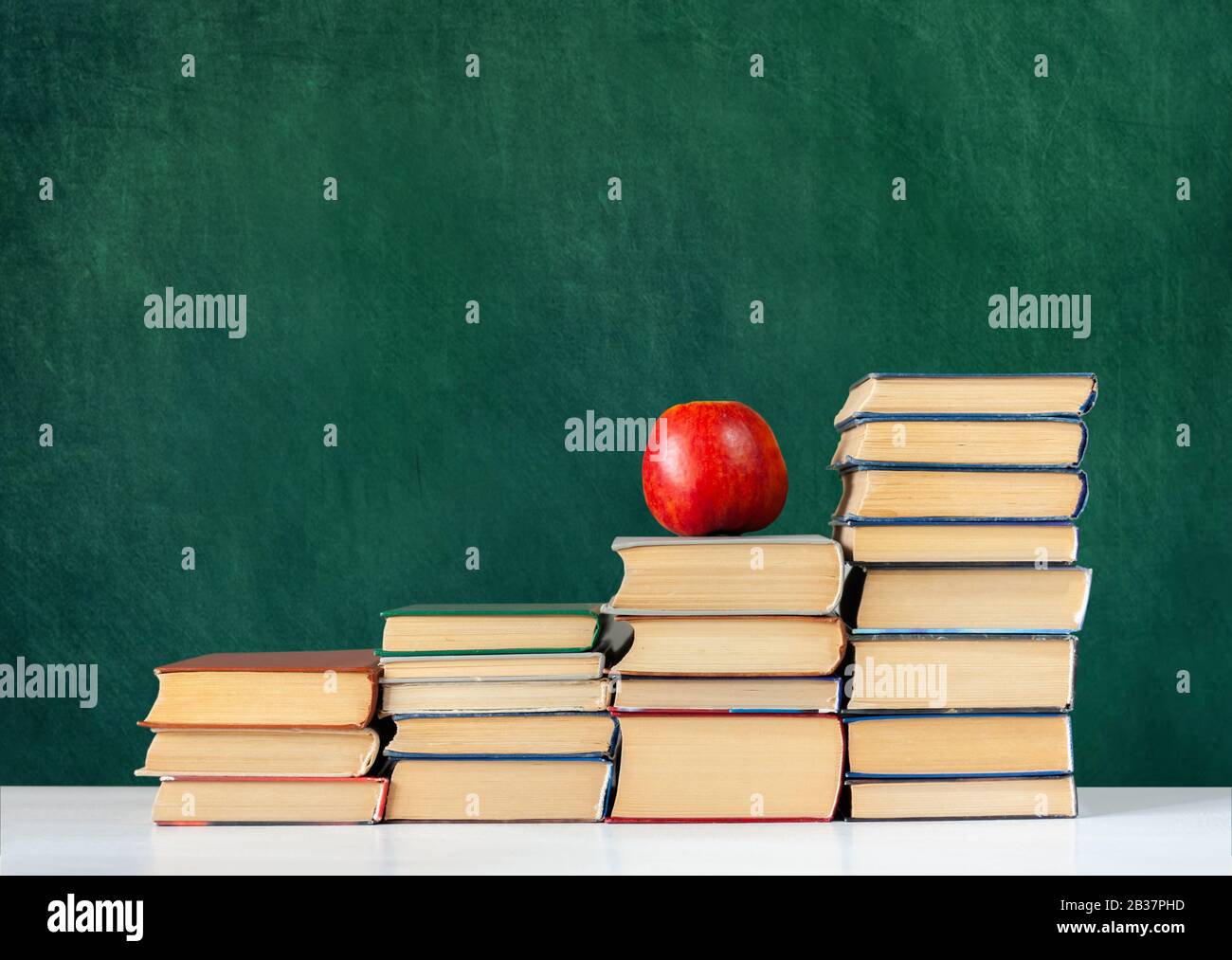 Back to school, pile of books and red apple with empty green school ...