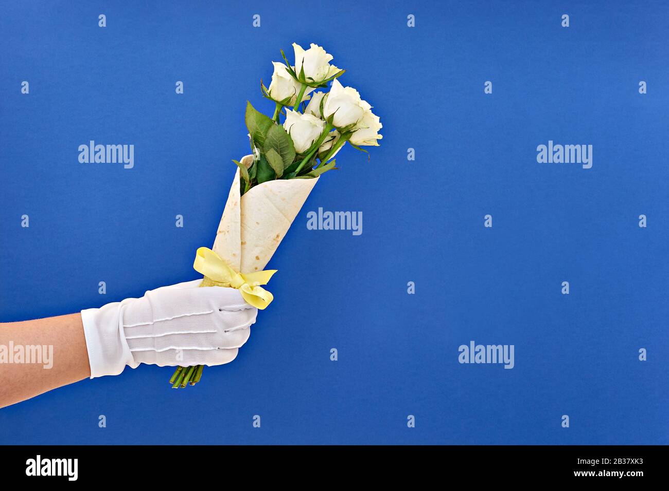 Steward's hand in white-glove holds bouquet of white roses wrapped in ...