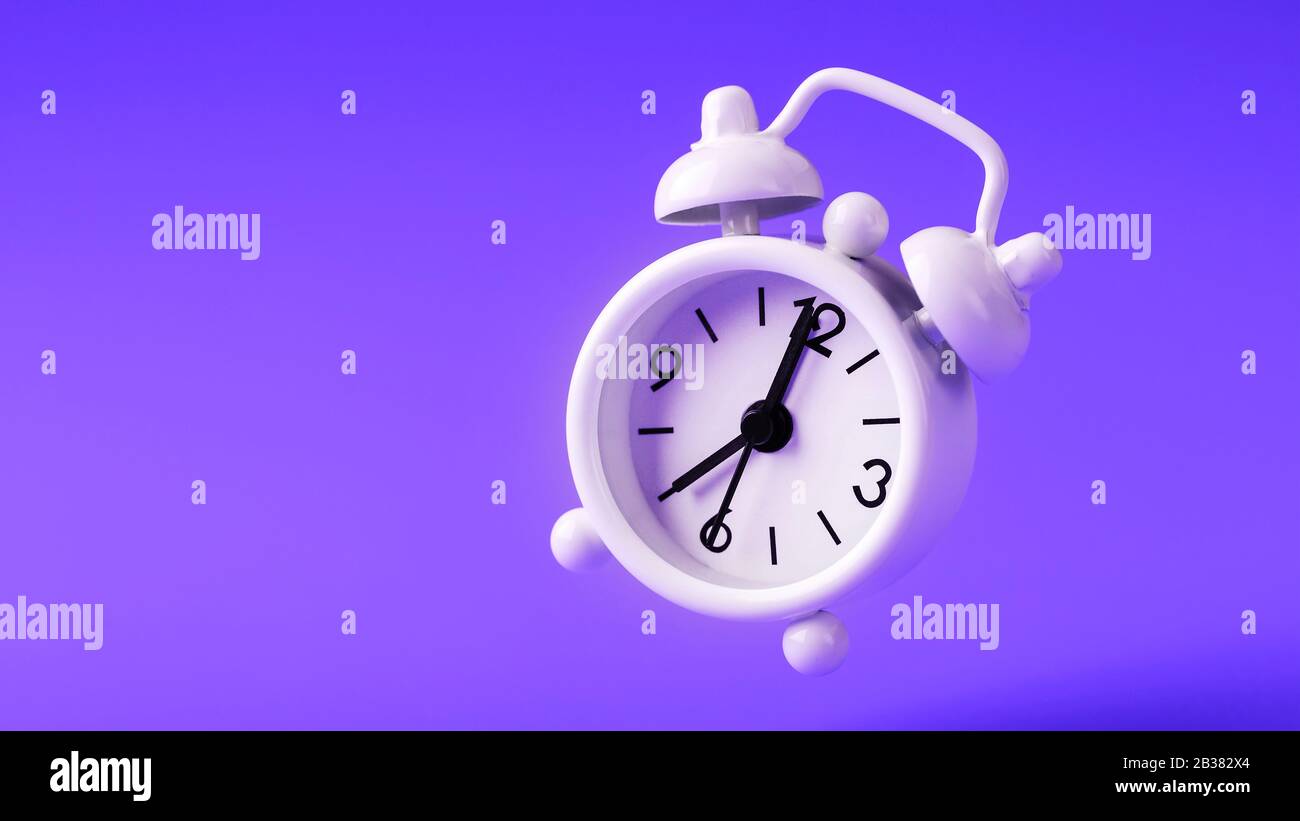 White retro style alarm clock in levitation isolated on purple ...