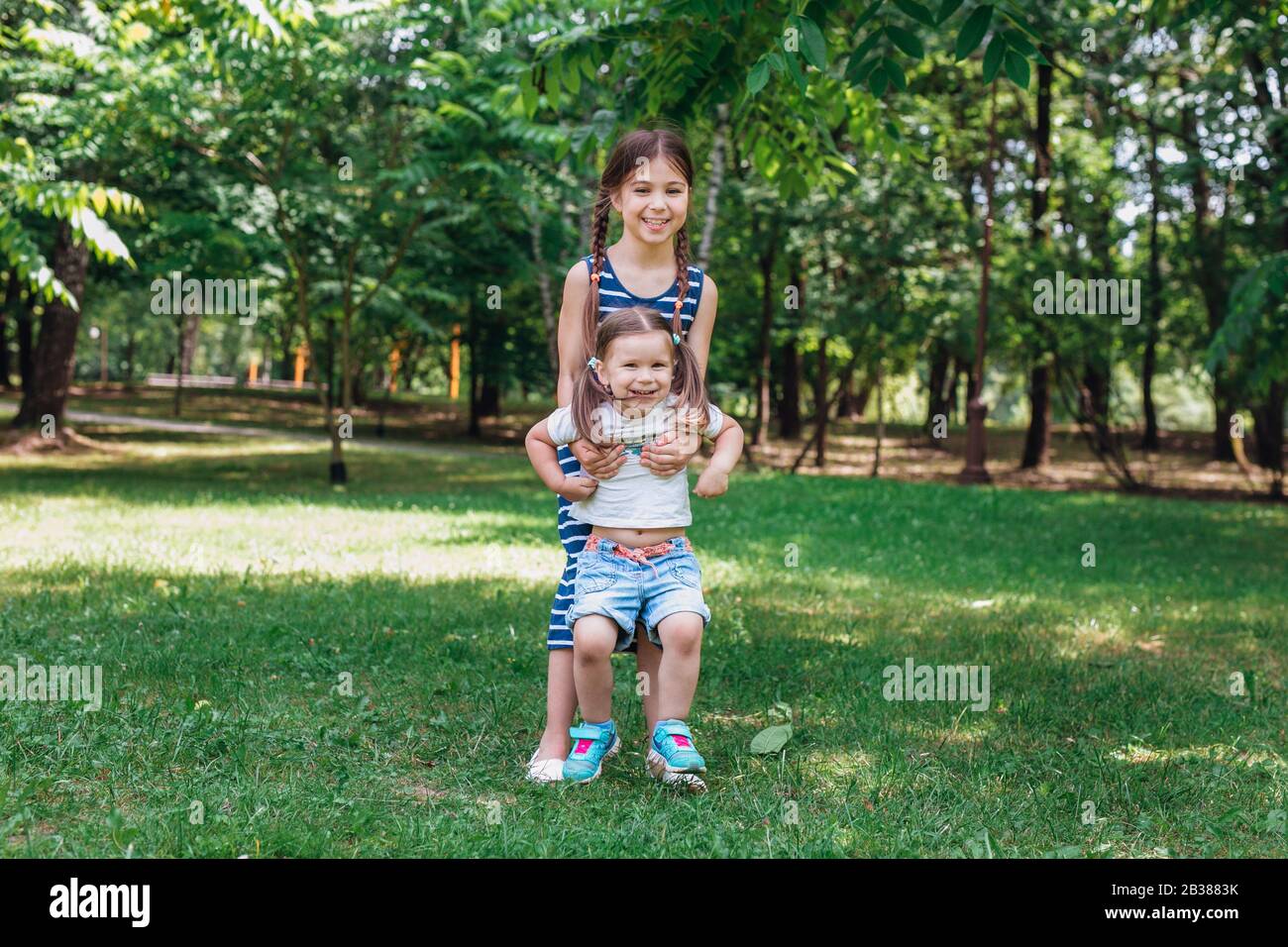 Two happy kids playing on green grass outdoors in summer park Stock ...