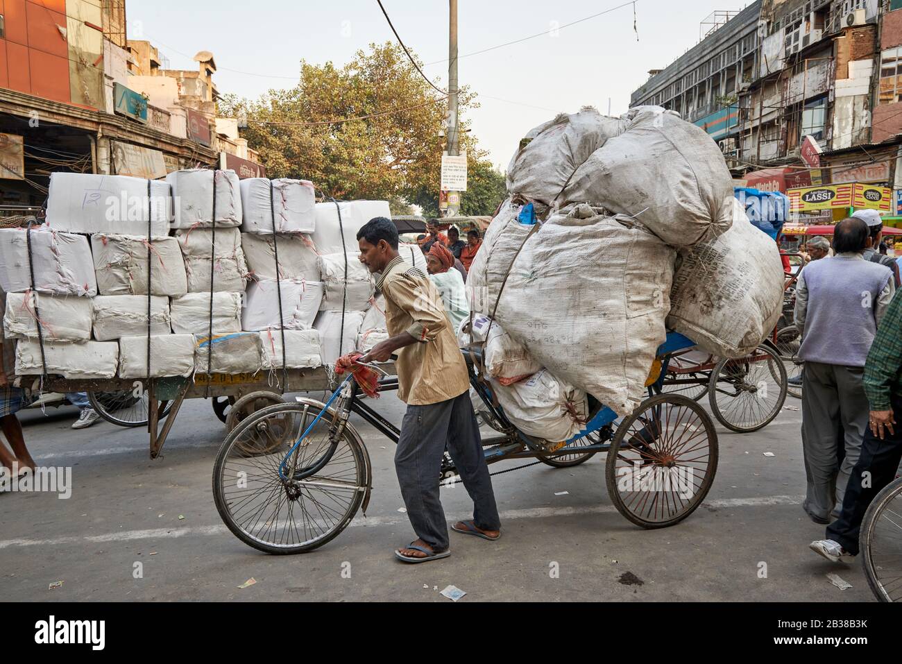 man with heavy loaded bicycle on Old Dehli spice market, shops in Swami ...