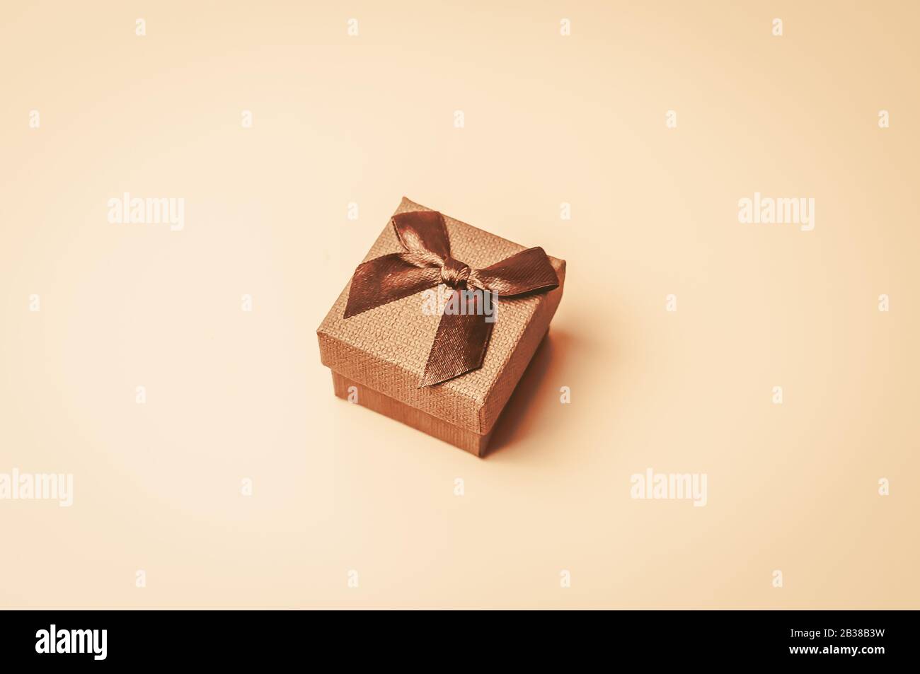 Vintage beige box with brown ribbon on a beige isolated background ...