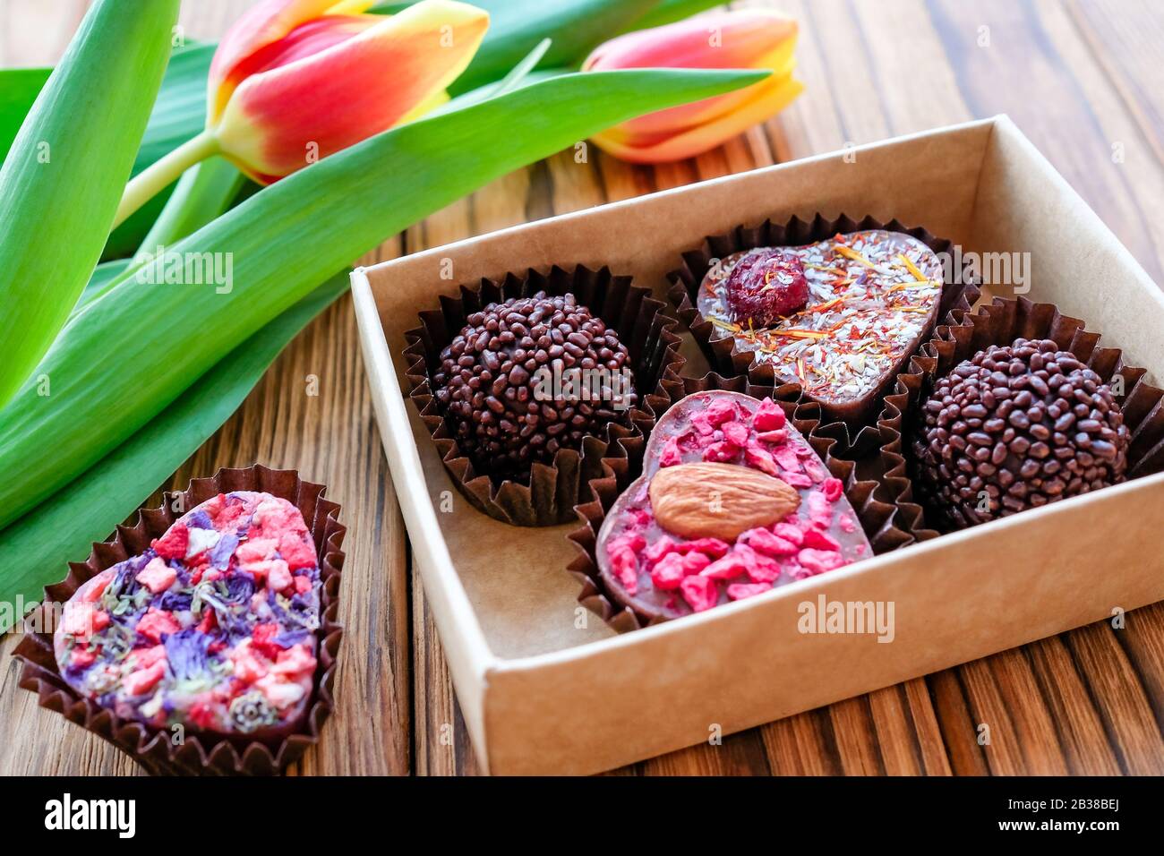 Handmade sweets in a box next to tulips for the holiday, wooden ...