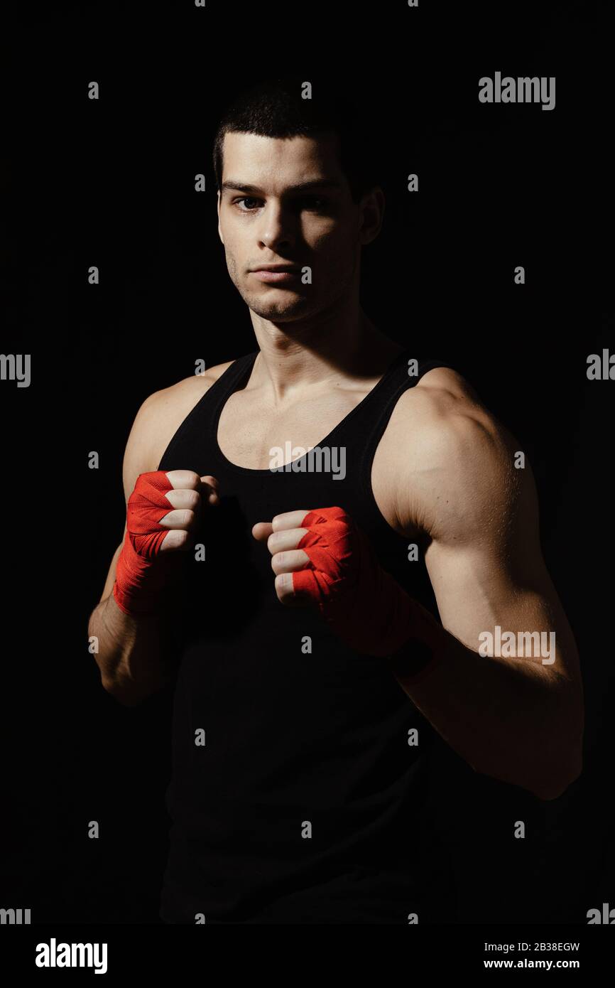 Boxing male portrait standing in a rack on black background with red ...