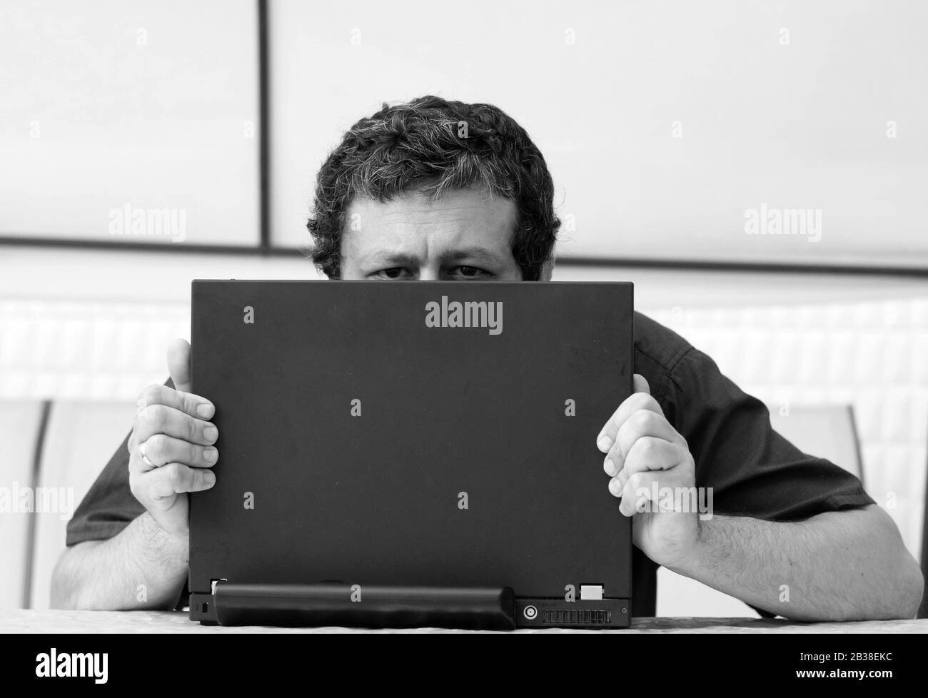 Serious programmer with his notebook hides face Stock Photo - Alamy
