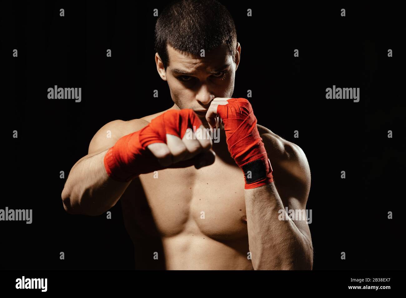 Athletic boxer punching with determination and precaution over black ...