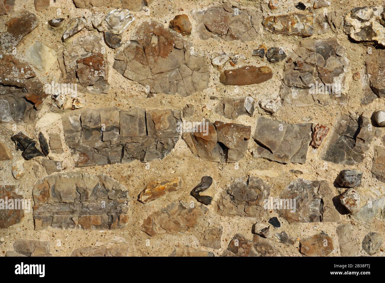 Old medieval castle wall in close up with flints and other stone set in ...