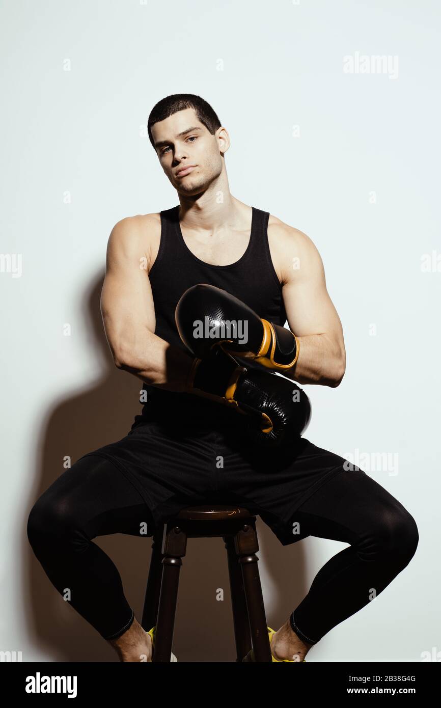 Boxer putting on his boxing gloves while resting on the chair on the ...