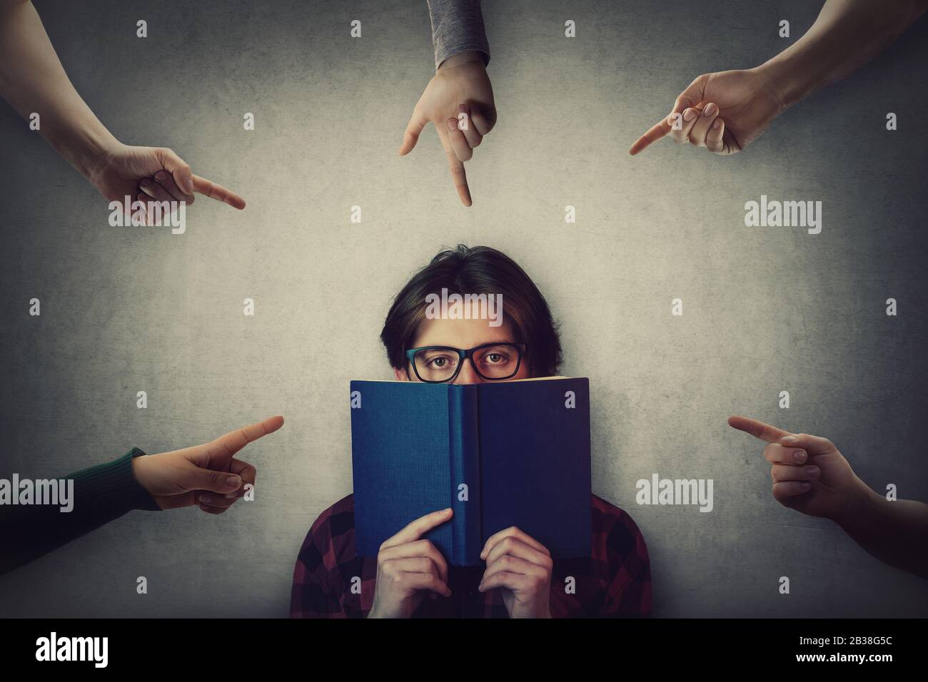 Student boy, school bullying victim, hiding behind an open book ...