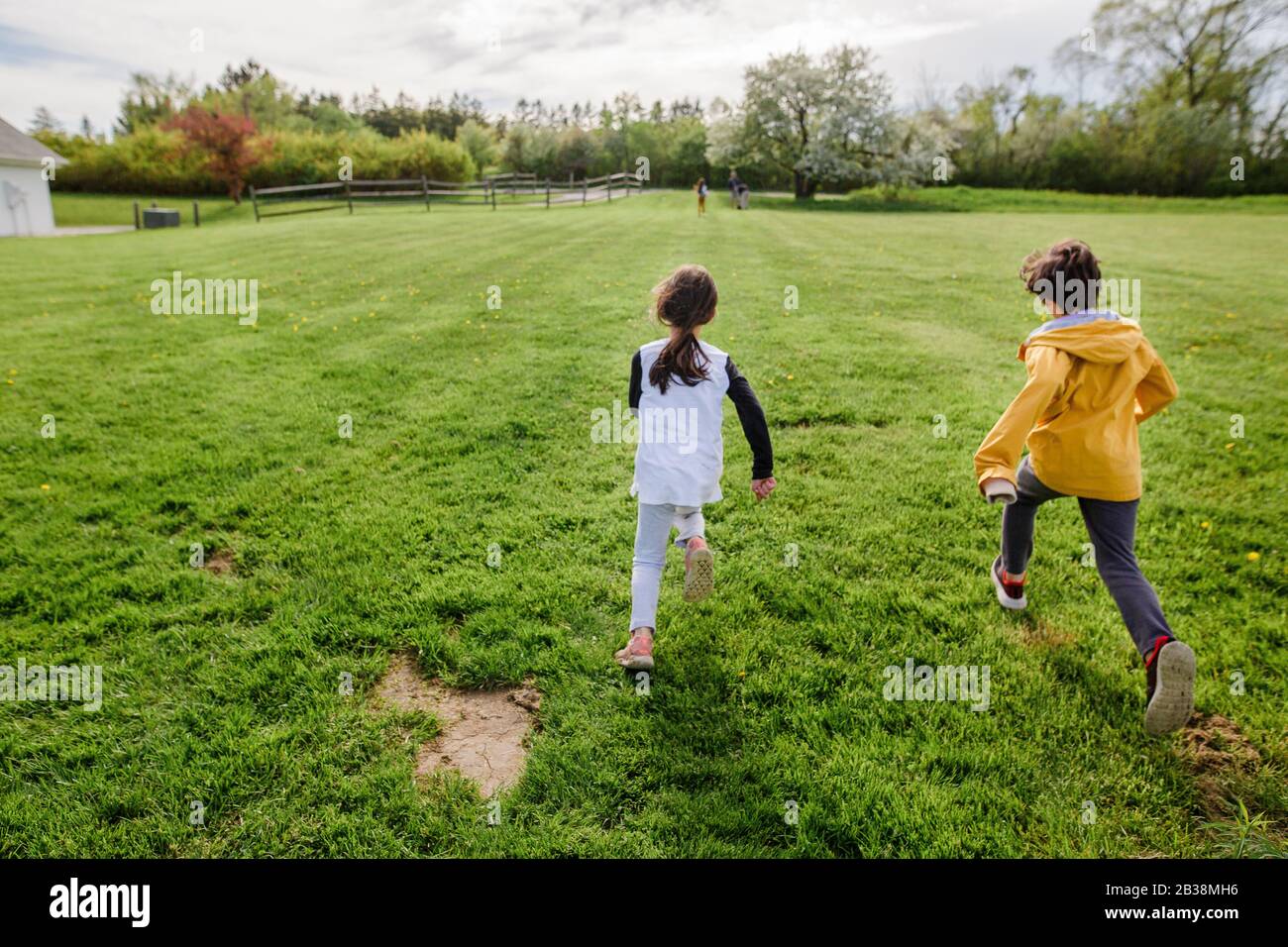 Three children run through a field at springtime, one far ahead Stock ...