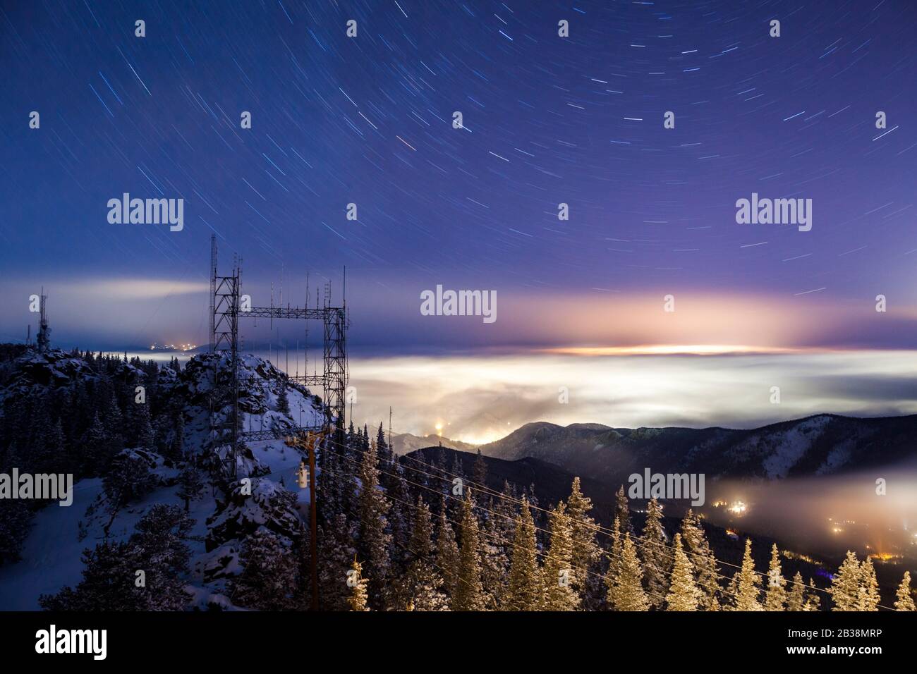 Communication towers, power lines, star trails, and low clouds lit by ...