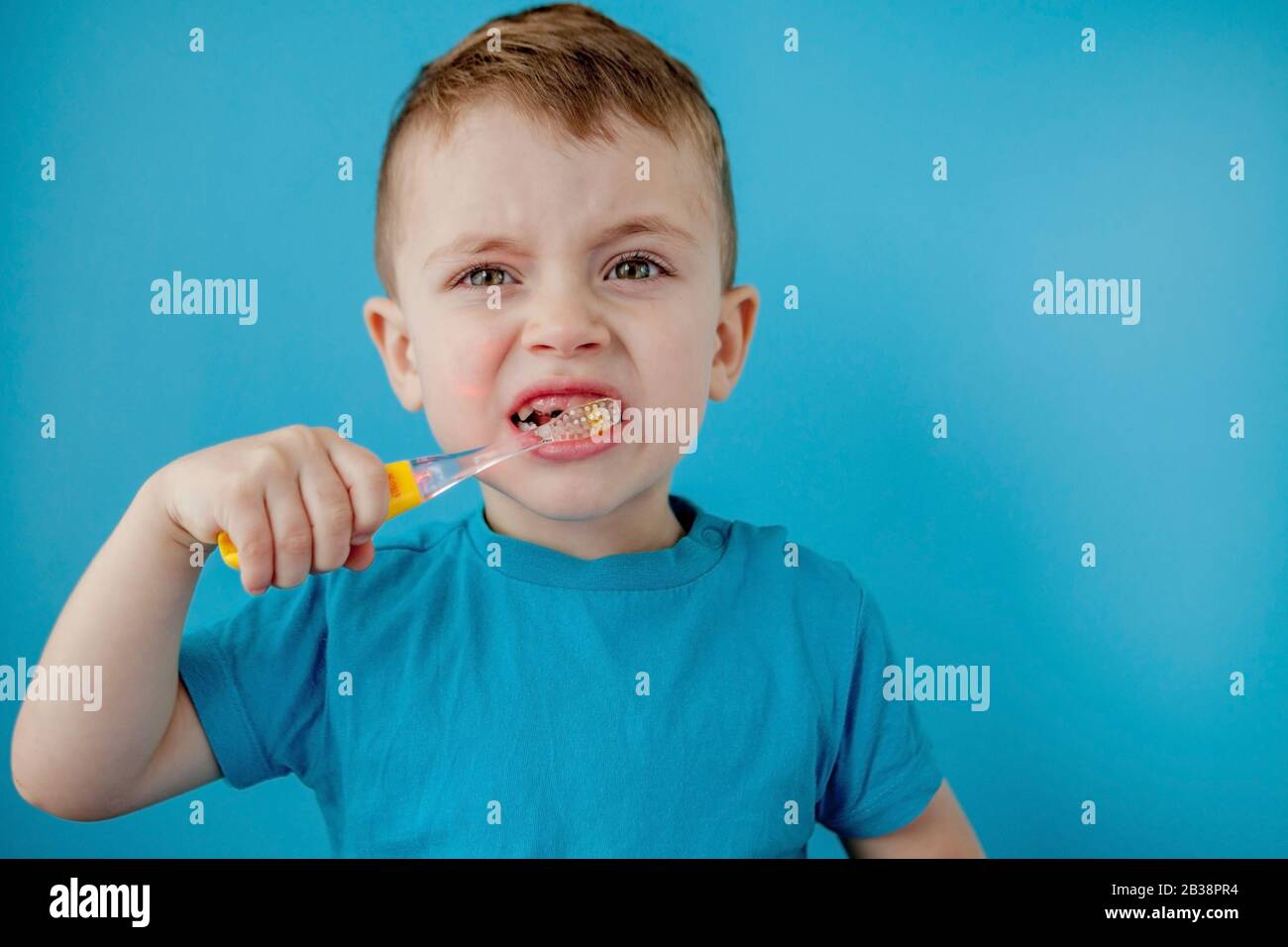 Little cute boy brushing his teeth on blue background Stock Photo - Alamy