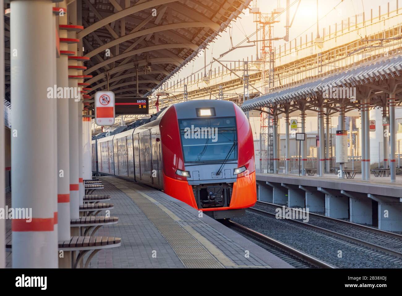 Passenger electric subway train arrives at a platform with benches for ...