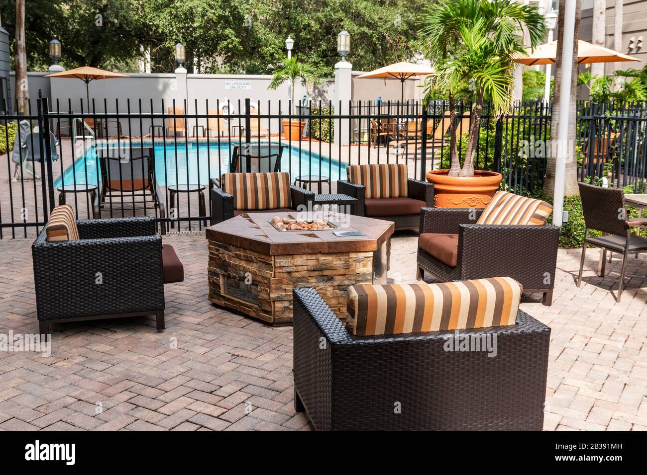 The patio of a hotel it set up with a ire pit, a pool and furniture to ...