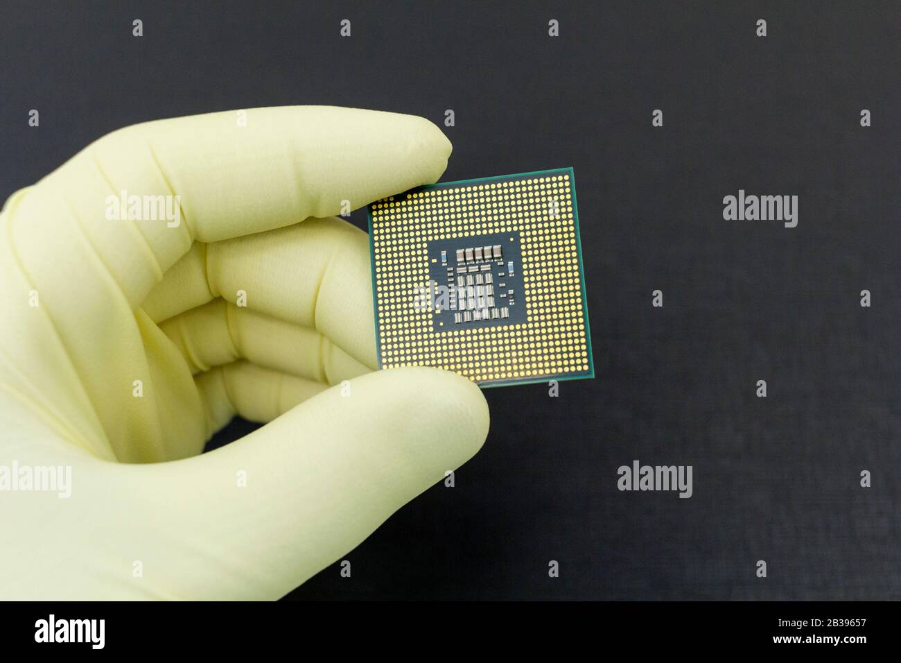 Hand in tight yellow glove holding a CPU computer processor microchip ...