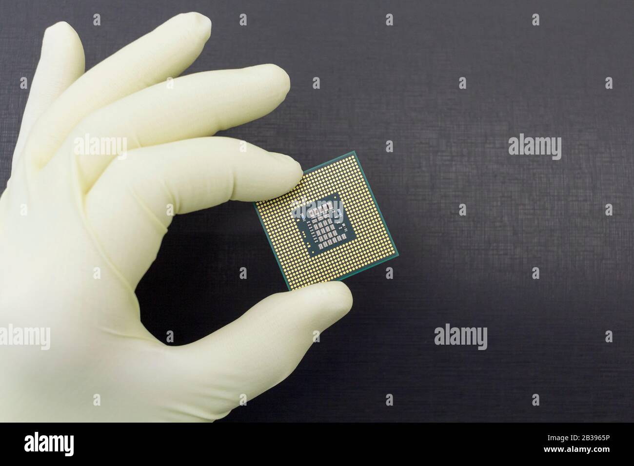Hand in tight yellow glove holding a CPU computer processor microchip ...