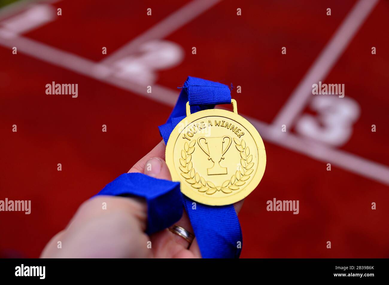 Gold medal , red running track in background, sport motivation concept ...