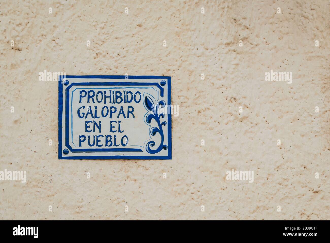 A sign indicating "Forbidden to gallop in the village" on a rough wall ...