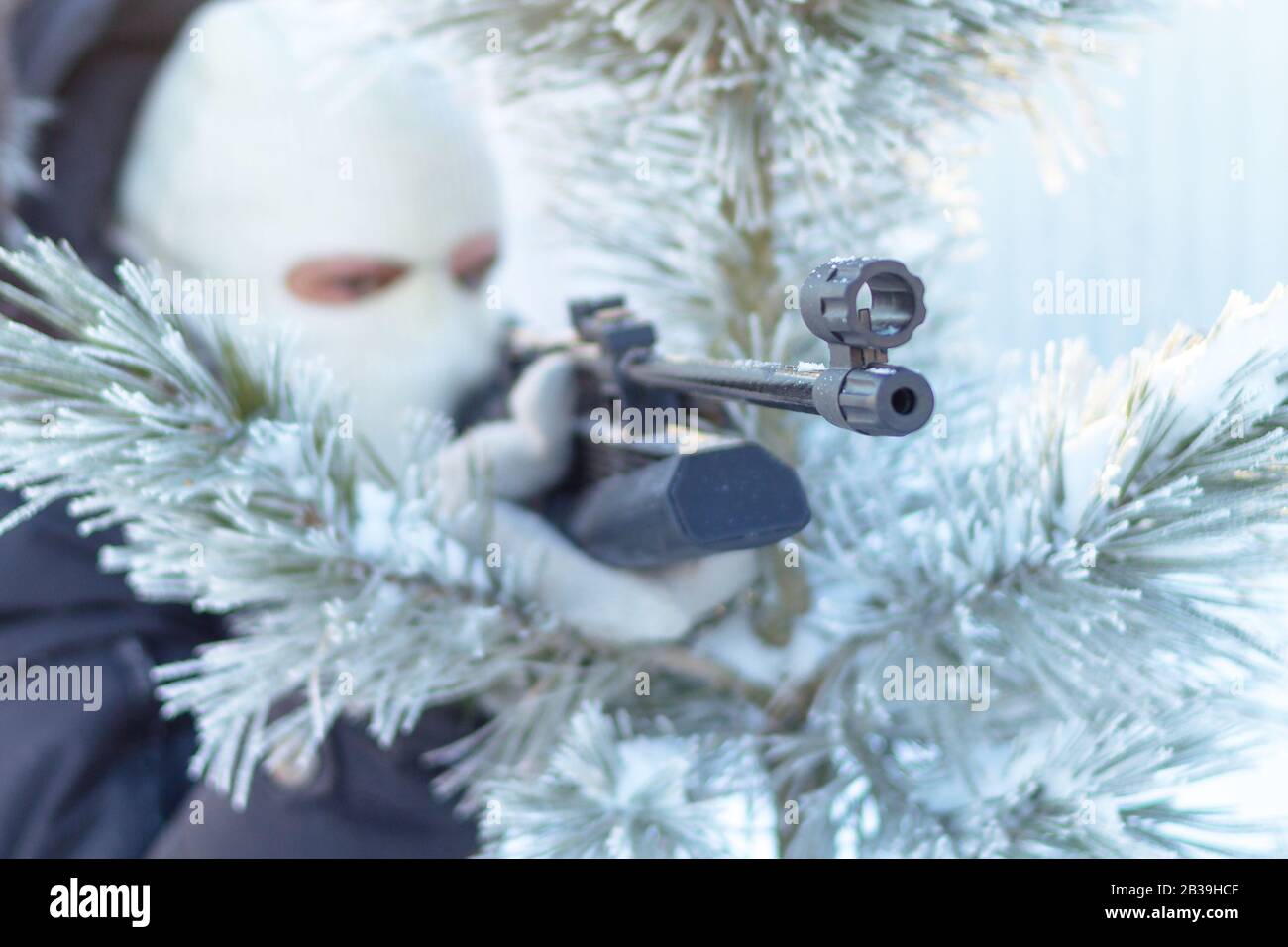Masked man aims with rifle in winter forest Stock Photo - Alamy