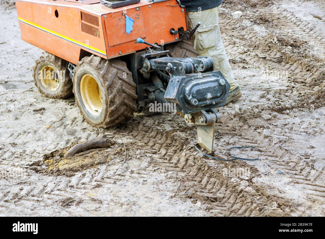 Small tractor is digging in the ground to lay water pipe for irrigation ...
