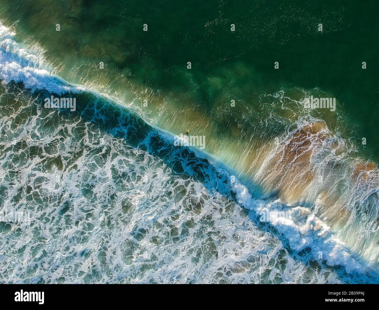 Drone view of beautiful turquiose sea waves breaking on sandy coastline ...