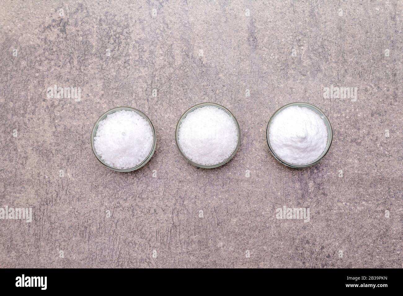Three types of sea salt - large, medium and small. Top view, on a gray ...