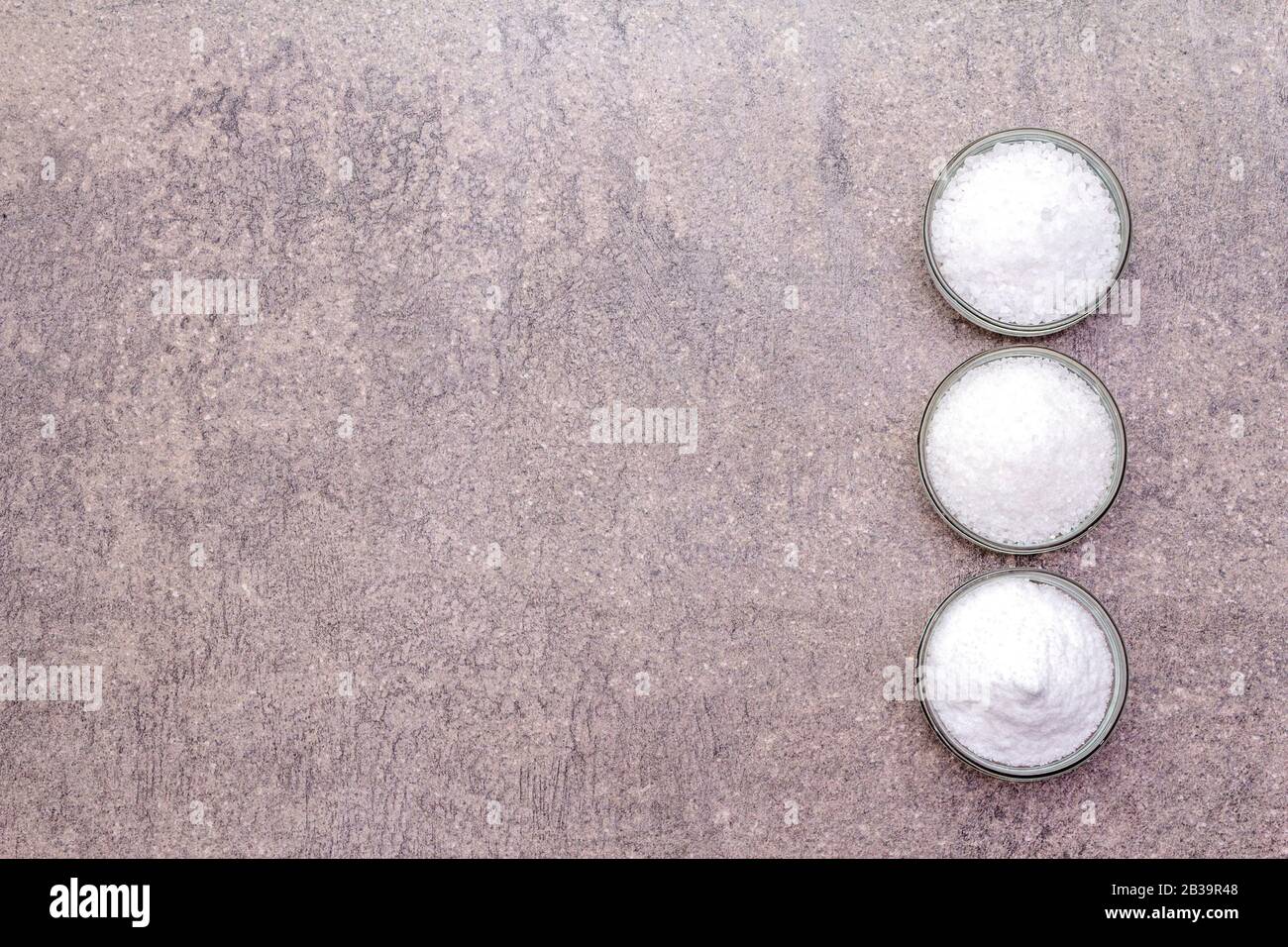 Three types of sea salt - large, medium and small. Top view, on a gray ...