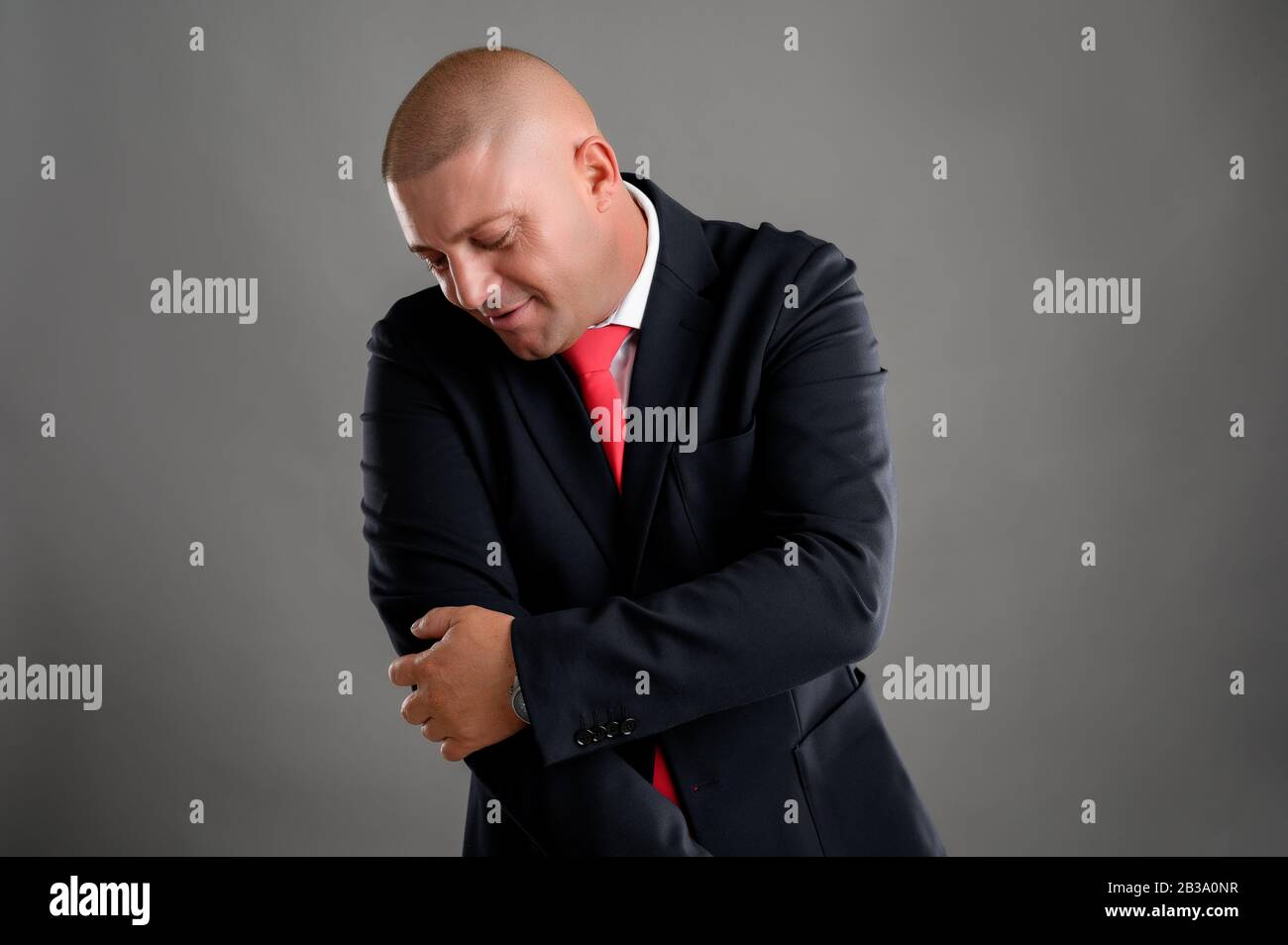 Businessman dressed in black suit having elbow pain from hard work ...