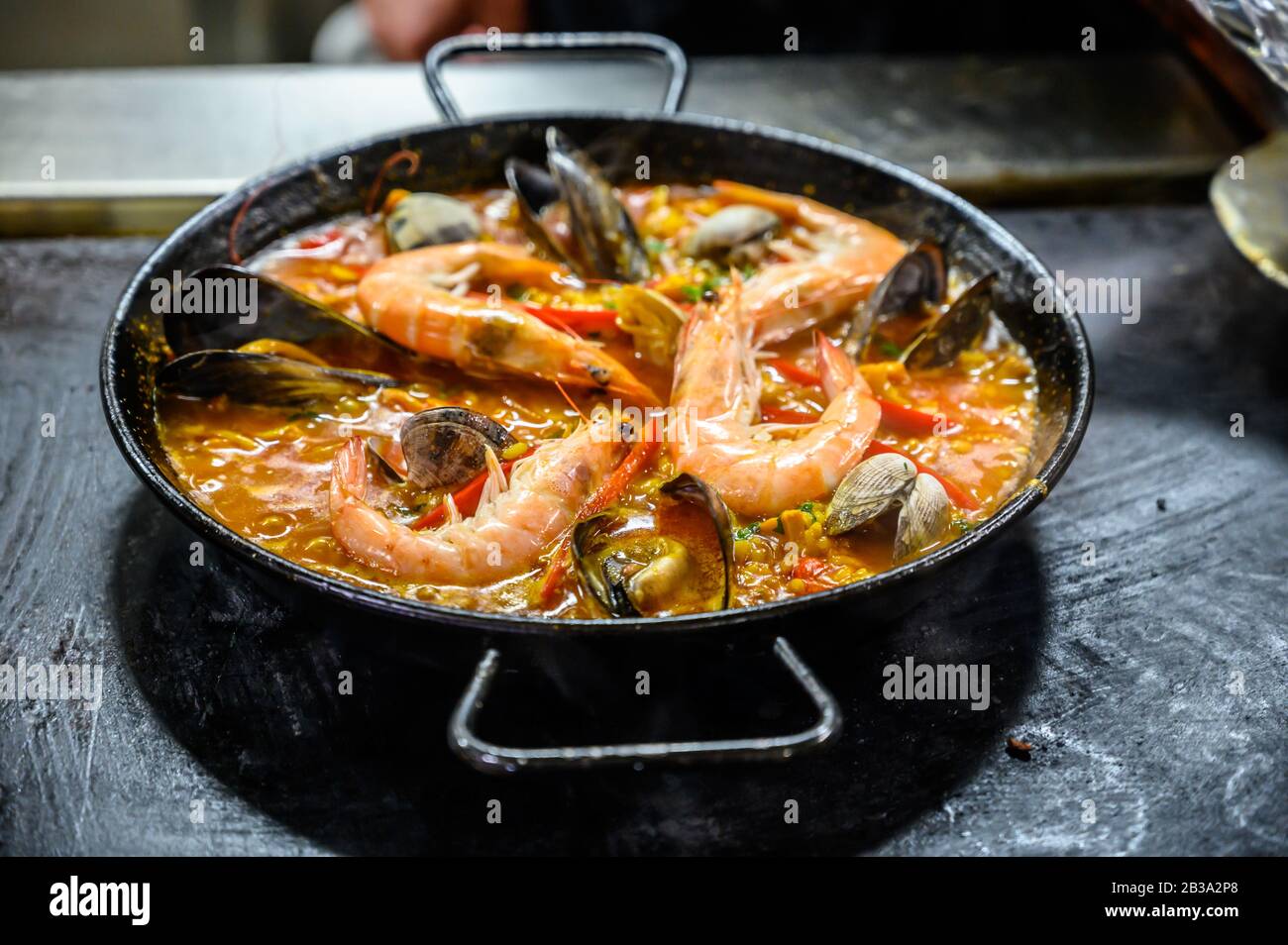 Spanish cuisine, cook making tasty paella, famous dish with rice and ...