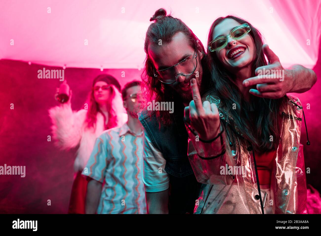 happy girl and man in sunglasses showing middle fingers in nightclub ...