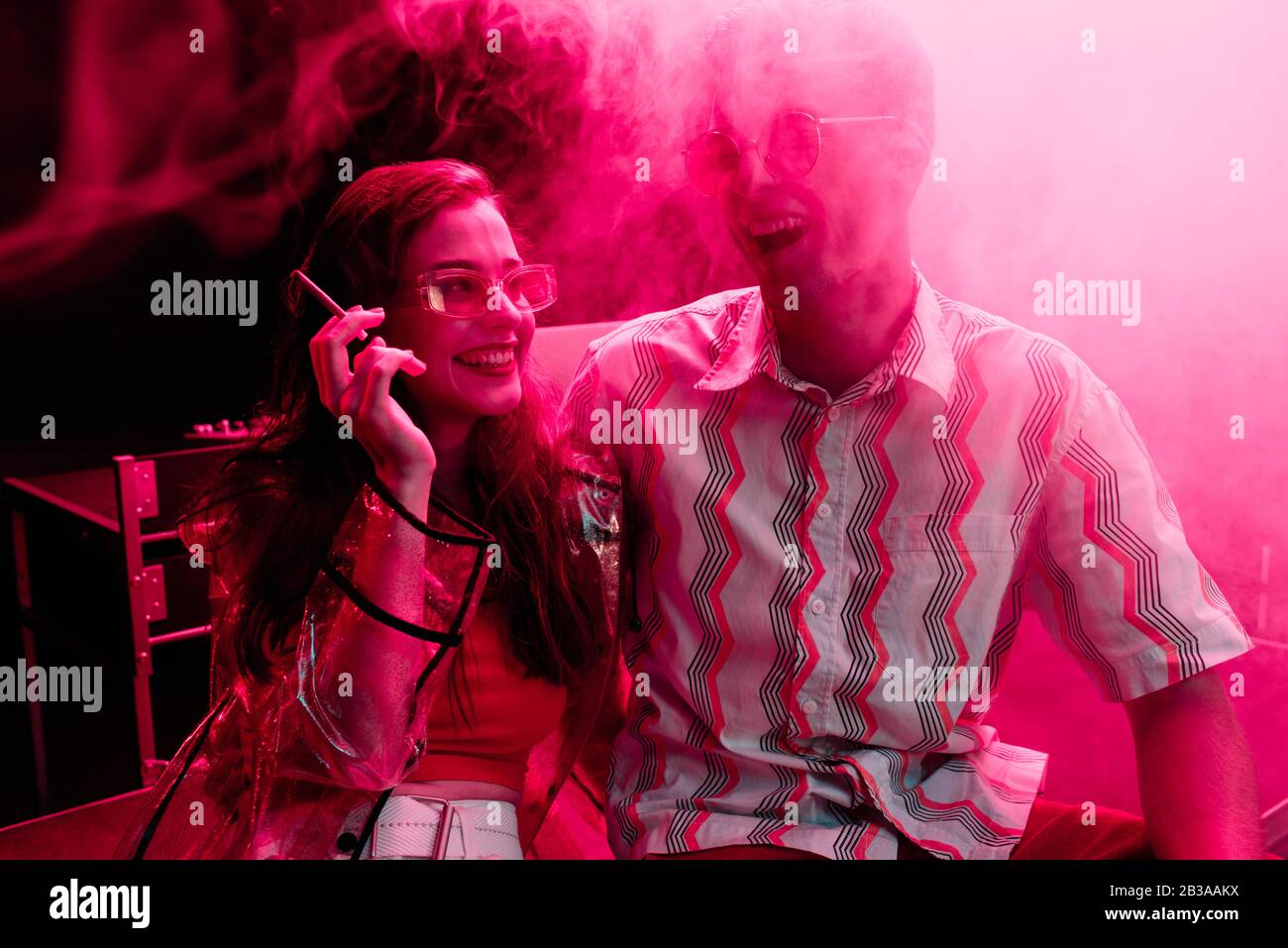 man and young woman with cigarette laughing during rave party in ...