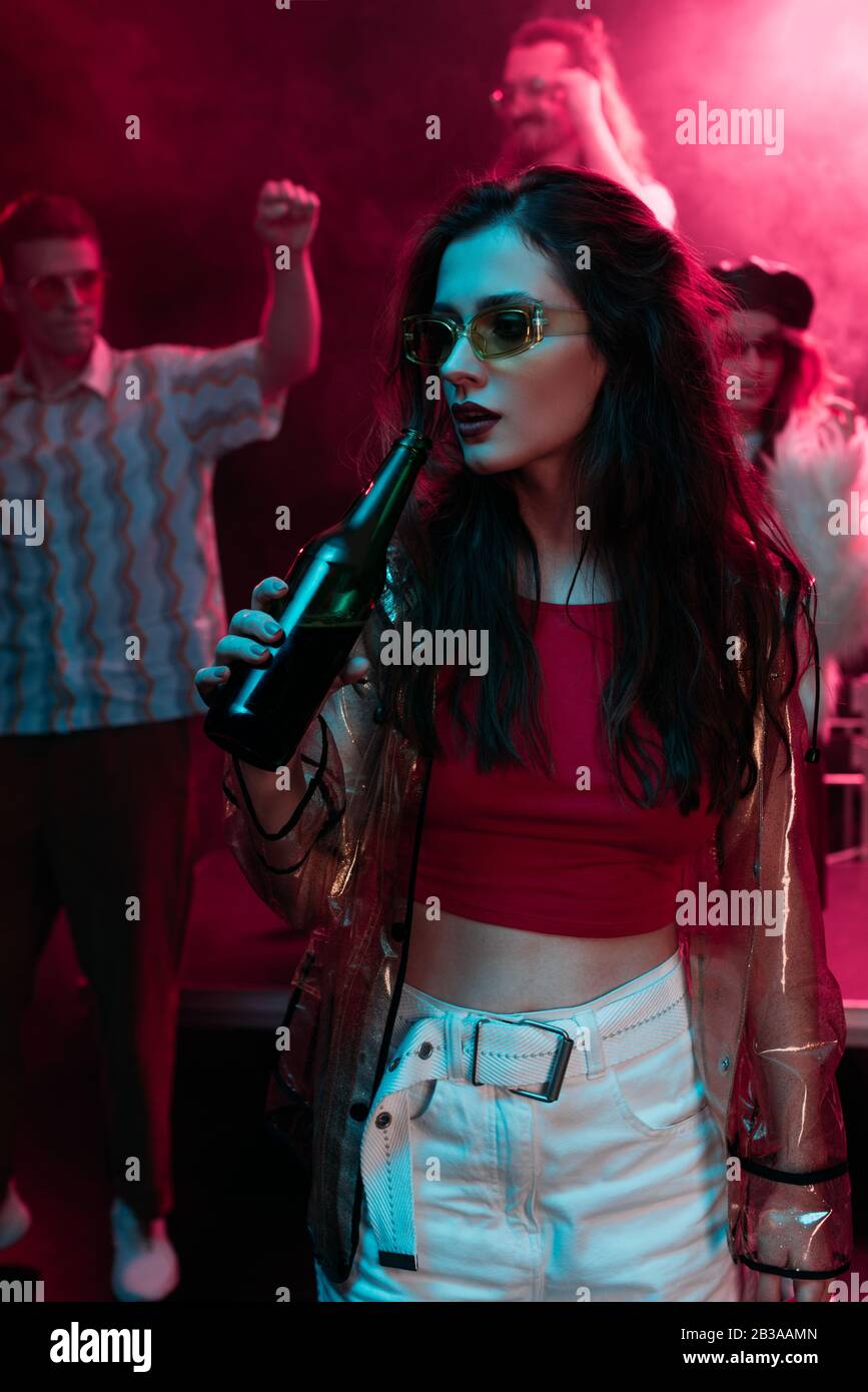 beautiful girl in sunglasses drinking beer in nightclub during rave ...