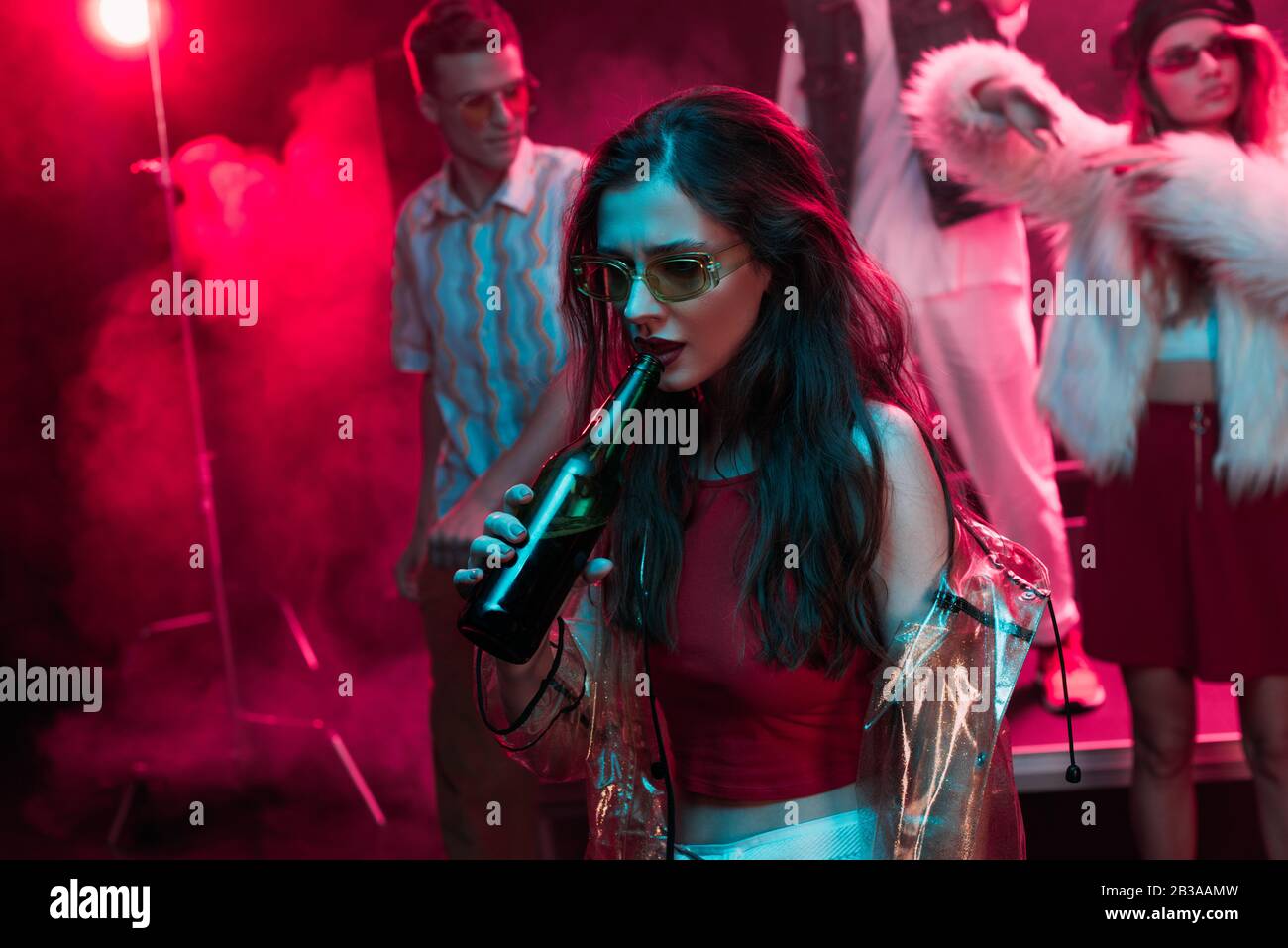 beautiful girl in sunglasses drinking beer in nightclub during rave ...