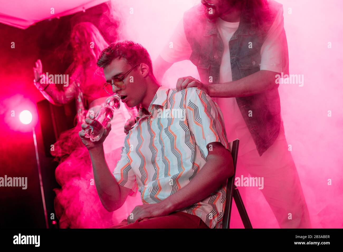 man checking on sick man sitting with bottle of water in nightclub ...