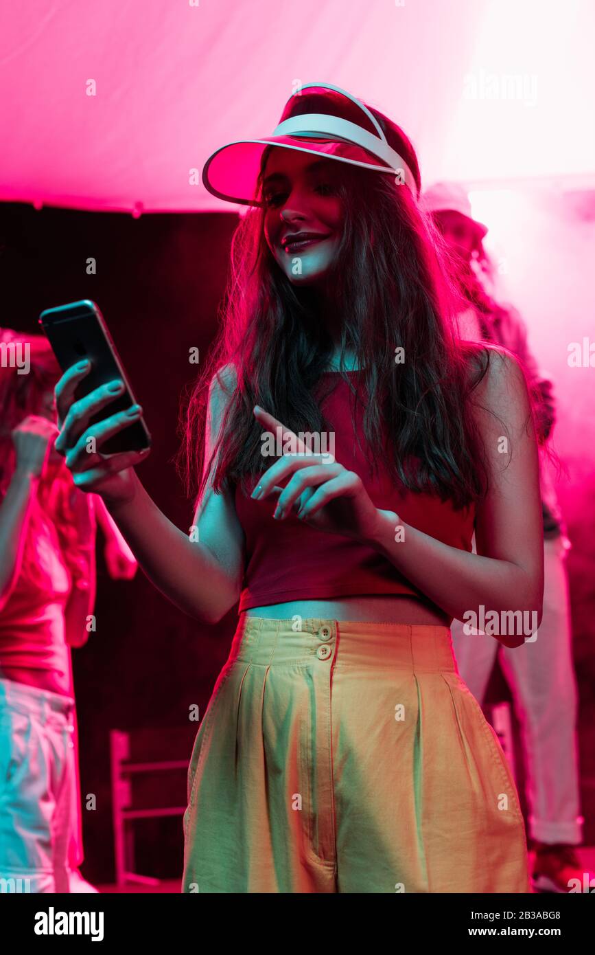 girl using smartphone and pointing with finger during rave party in ...